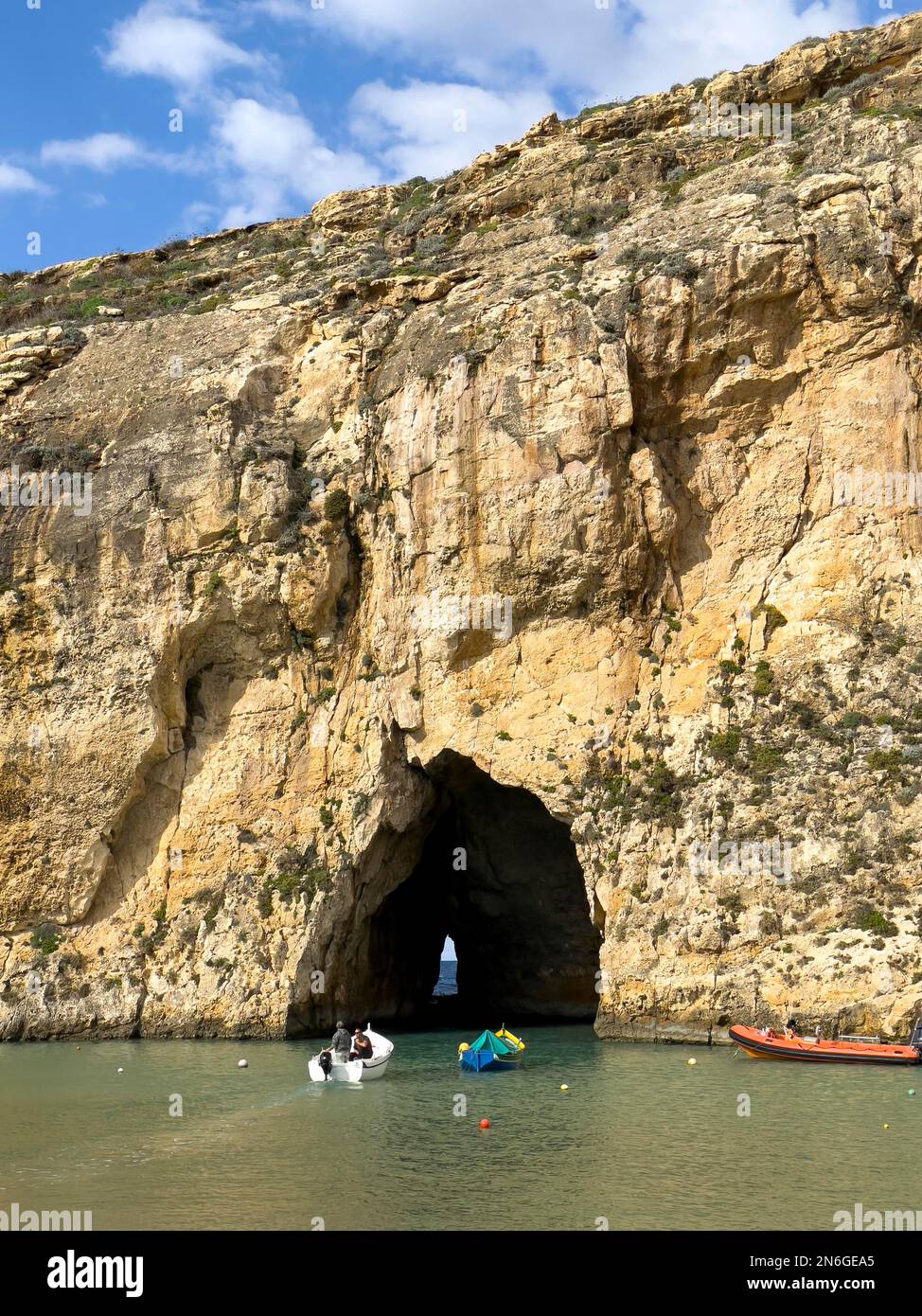 Small fishing boat sails in inland sea of Gozo in tunnel from passage ...