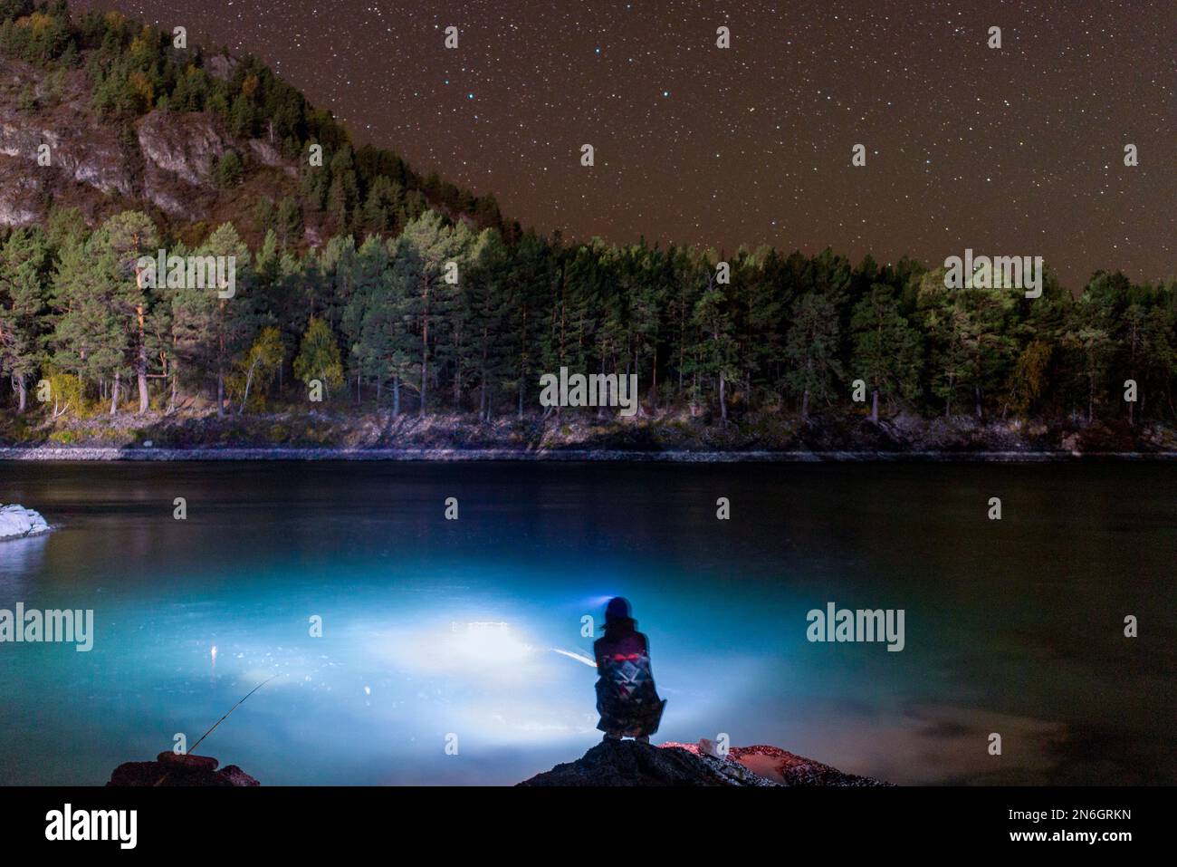 Silhouette of a fisherman girl sitting with a fishing rod with a ...