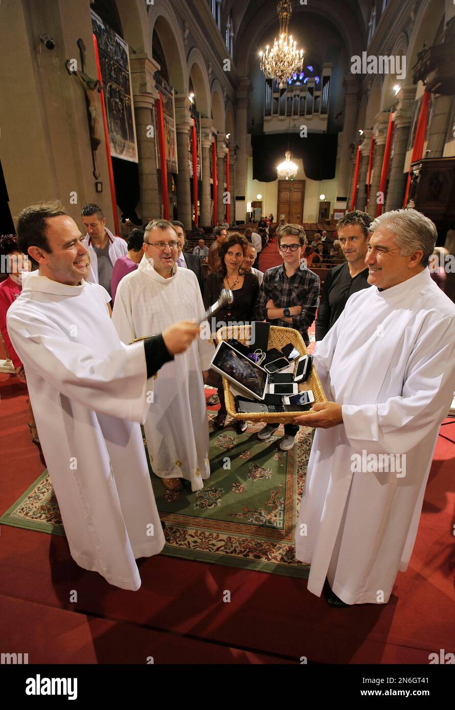 Parish priest Yves Marie Lequin, left, blesses mobile phones and ...