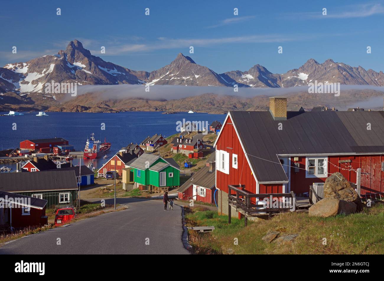 Simple houses and road, fjord and coastal fog, mountains with snow ...
