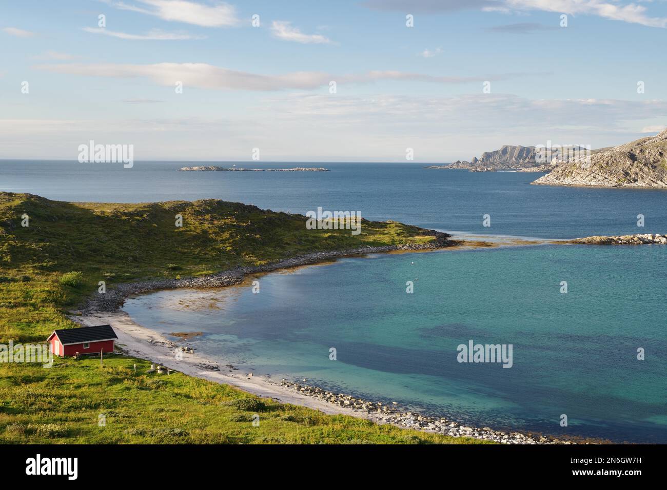 Green land with barren, rocky mountains, single cabin on a wide curving ...