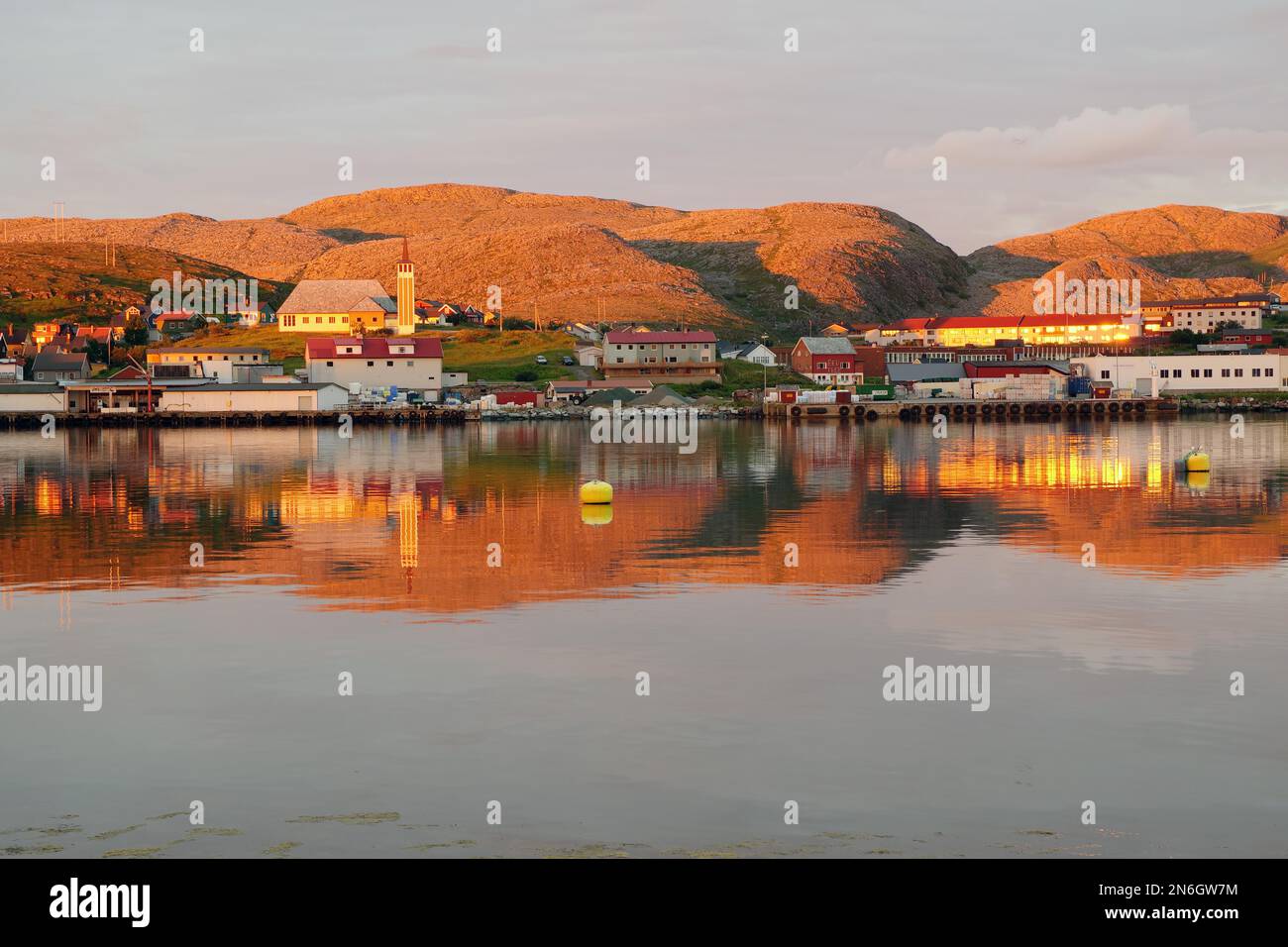 View of small fishing boats, houses and barren mountains in the evening ...