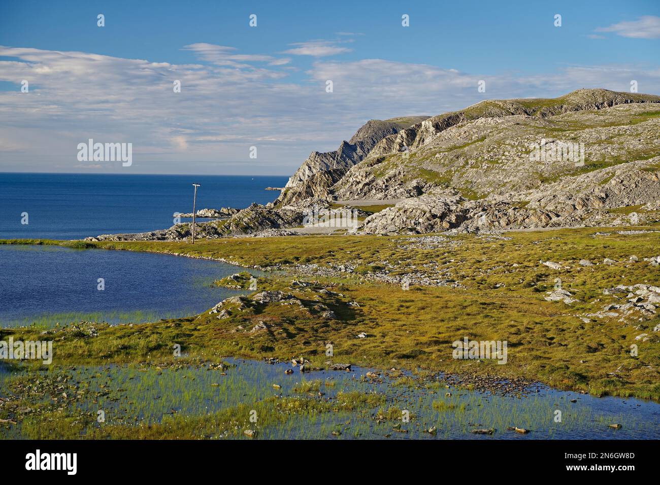 Green land with barren, stony mountains, single ponds, Arctic Sea ...