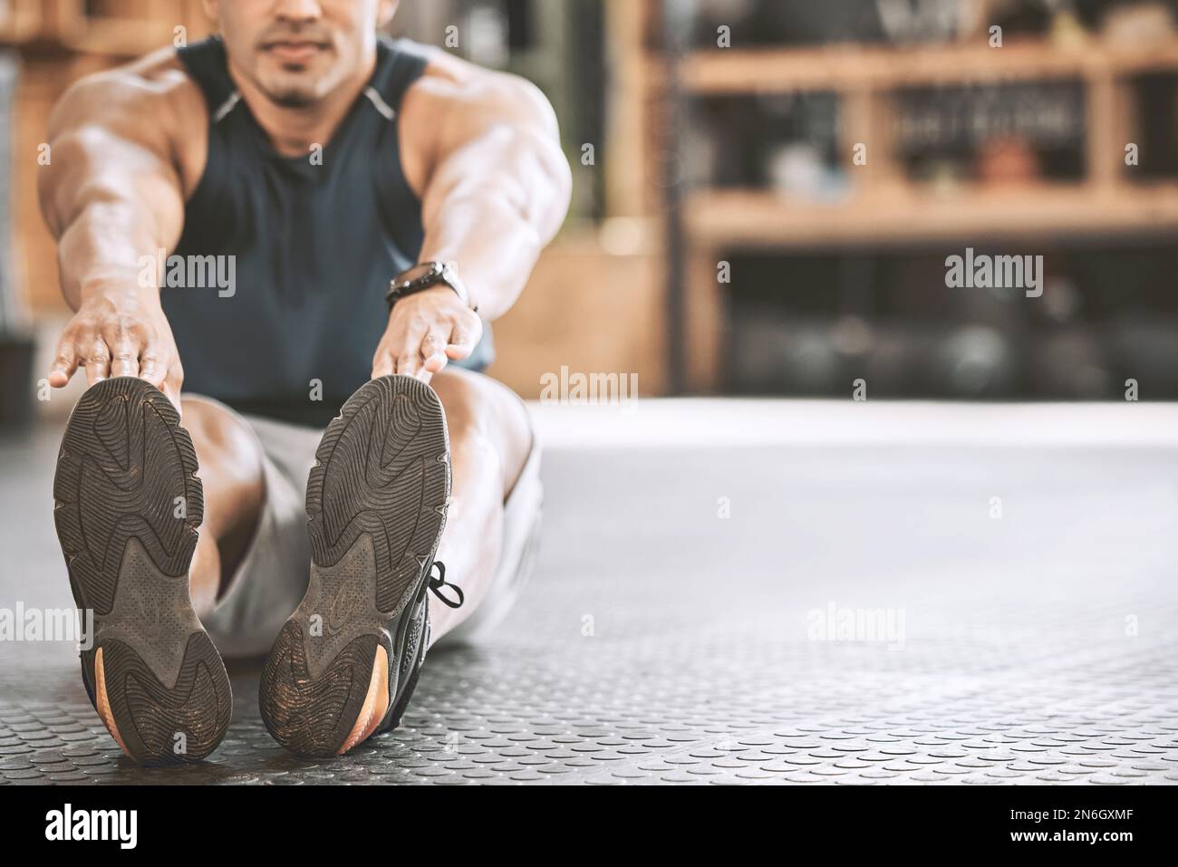 Fit man stretching his leg. Bodybuilding sitting on gym floor for a ...