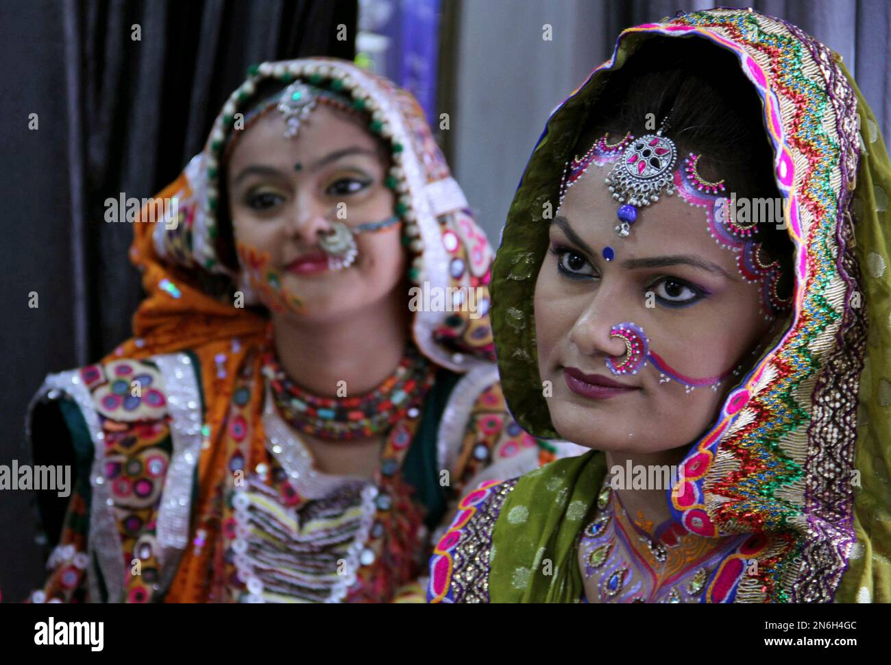 Indian girls dressed in traditional finery wait to perform the Garba ...
