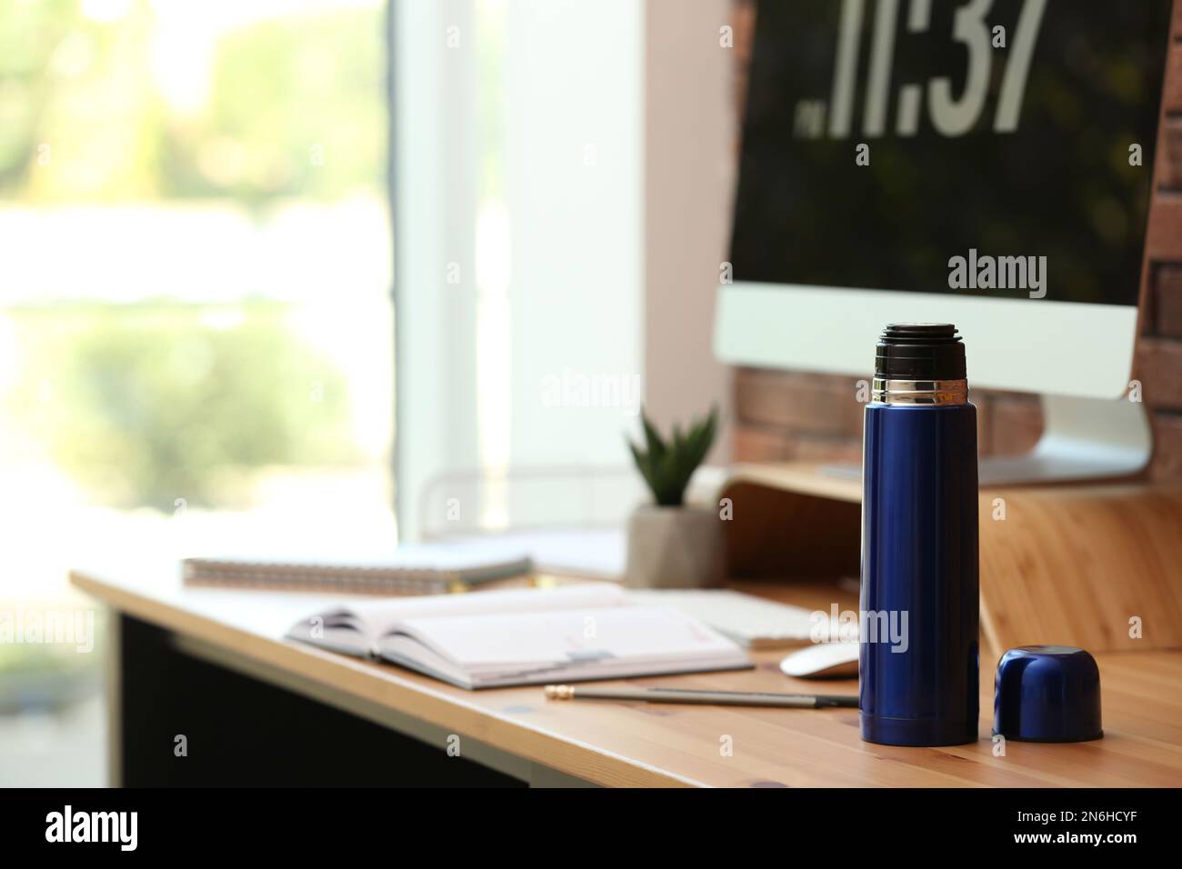 Modern thermos on wooden desk at workplace. Space for text Stock Photo ...