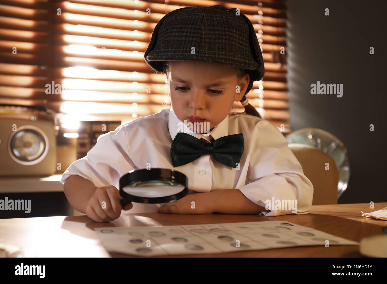 Cute little detective exploring fingerprints with magnifying glass at ...
