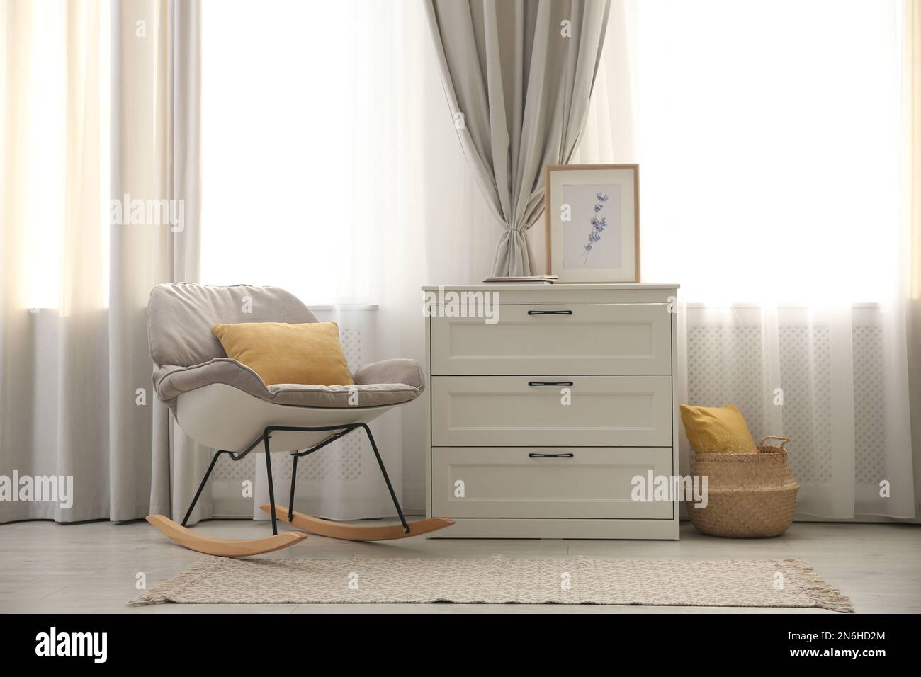 Rocking chair and chest of drawers near window with stylish curtains in ...