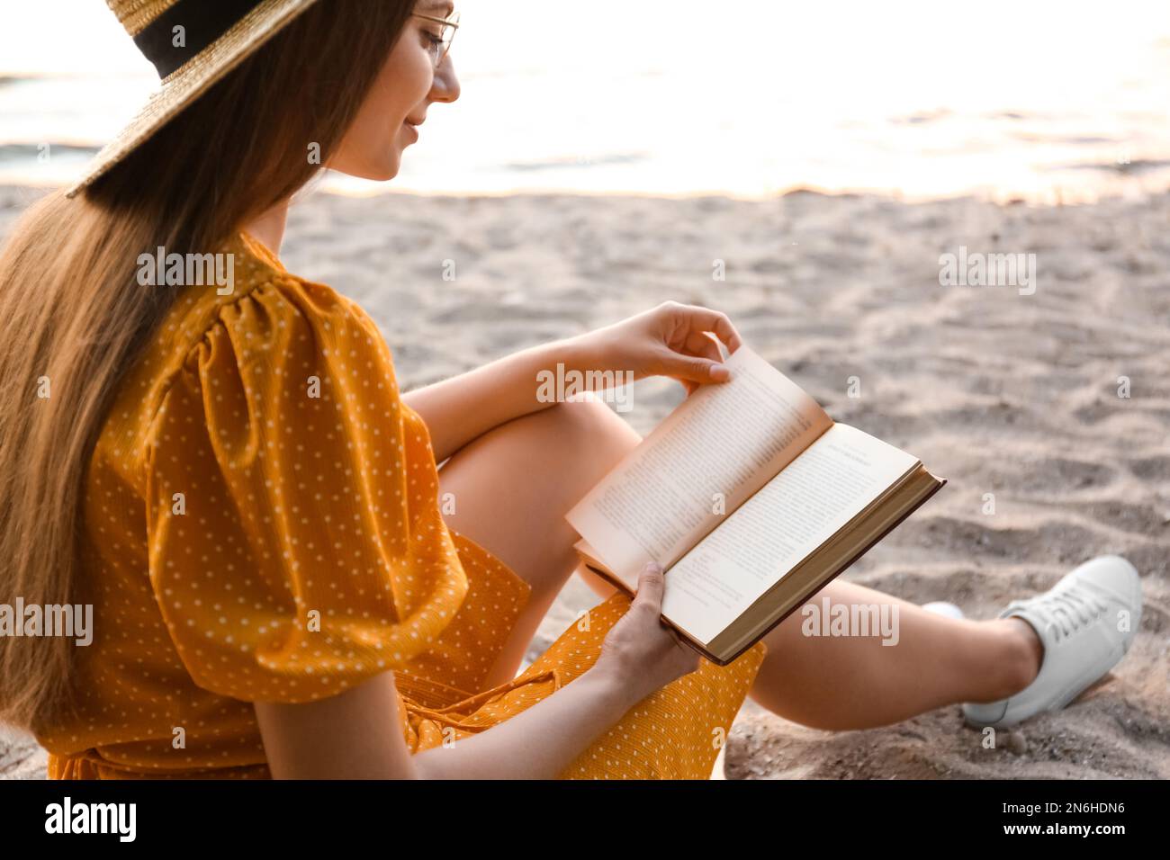 Young woman reading book on sandy beach Stock Photo - Alamy