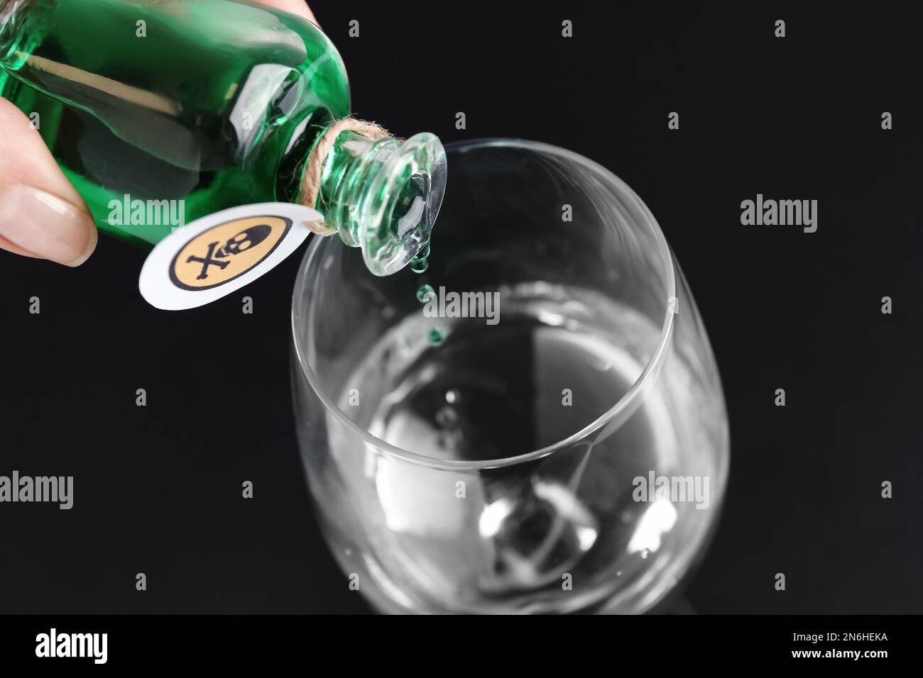 Woman pouring poison into glass of water on black background, closeup ...