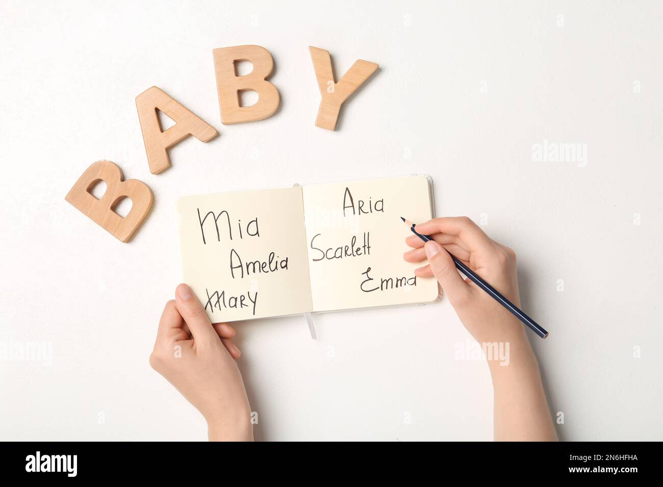 Woman choosing baby name at white table, top view Stock Photo - Alamy