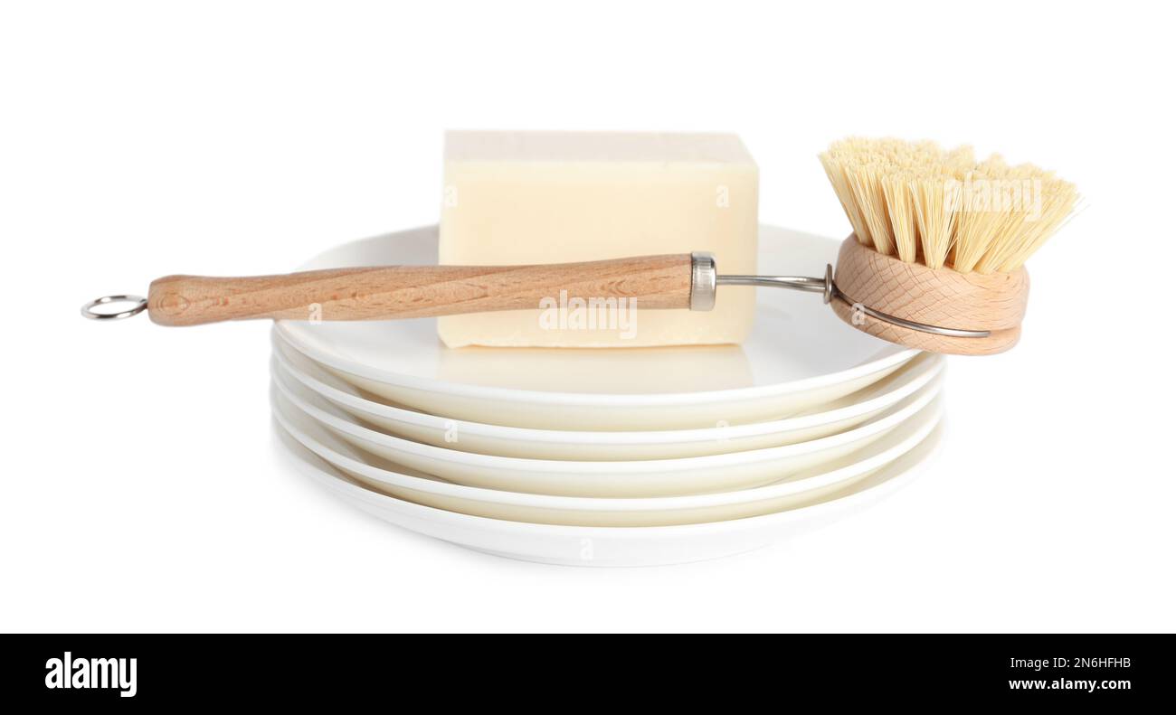 Cleaning brush and soap bar for dish washing on plates against white ...