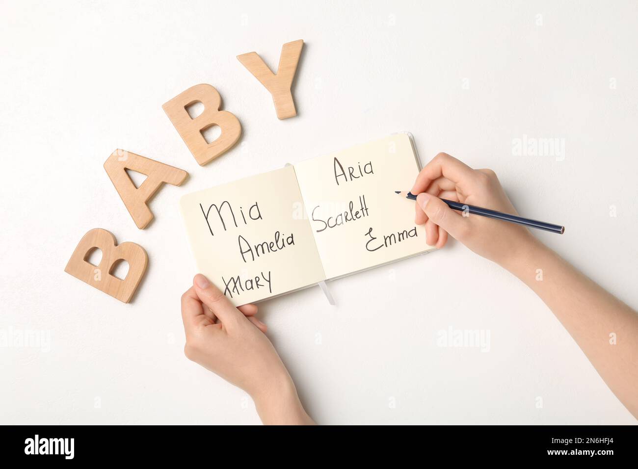 Woman choosing baby name at white table, top view Stock Photo - Alamy