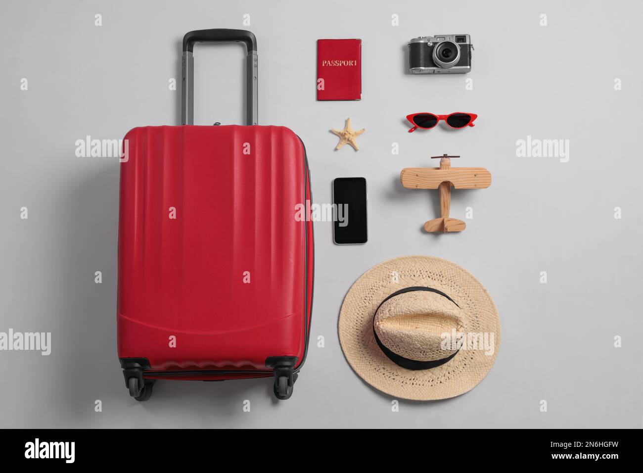 Flat lay composition with suitcase and travel accessories on grey ...