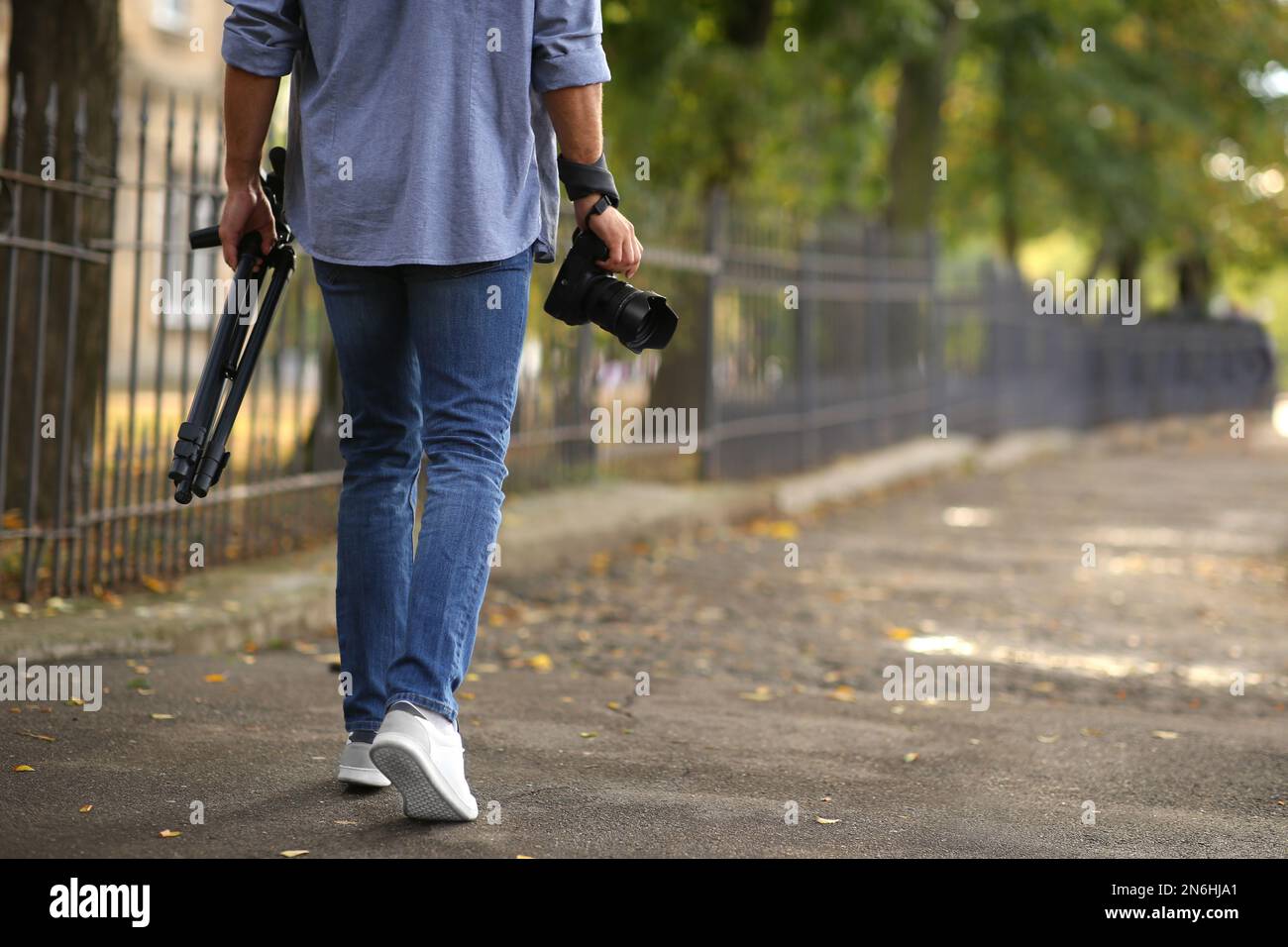 Photographer with professional camera and tripod outdoors, closeup ...