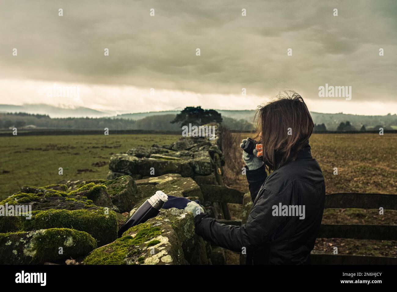 A woman drinking from a flask of coffee on a winter walk in the Wye ...