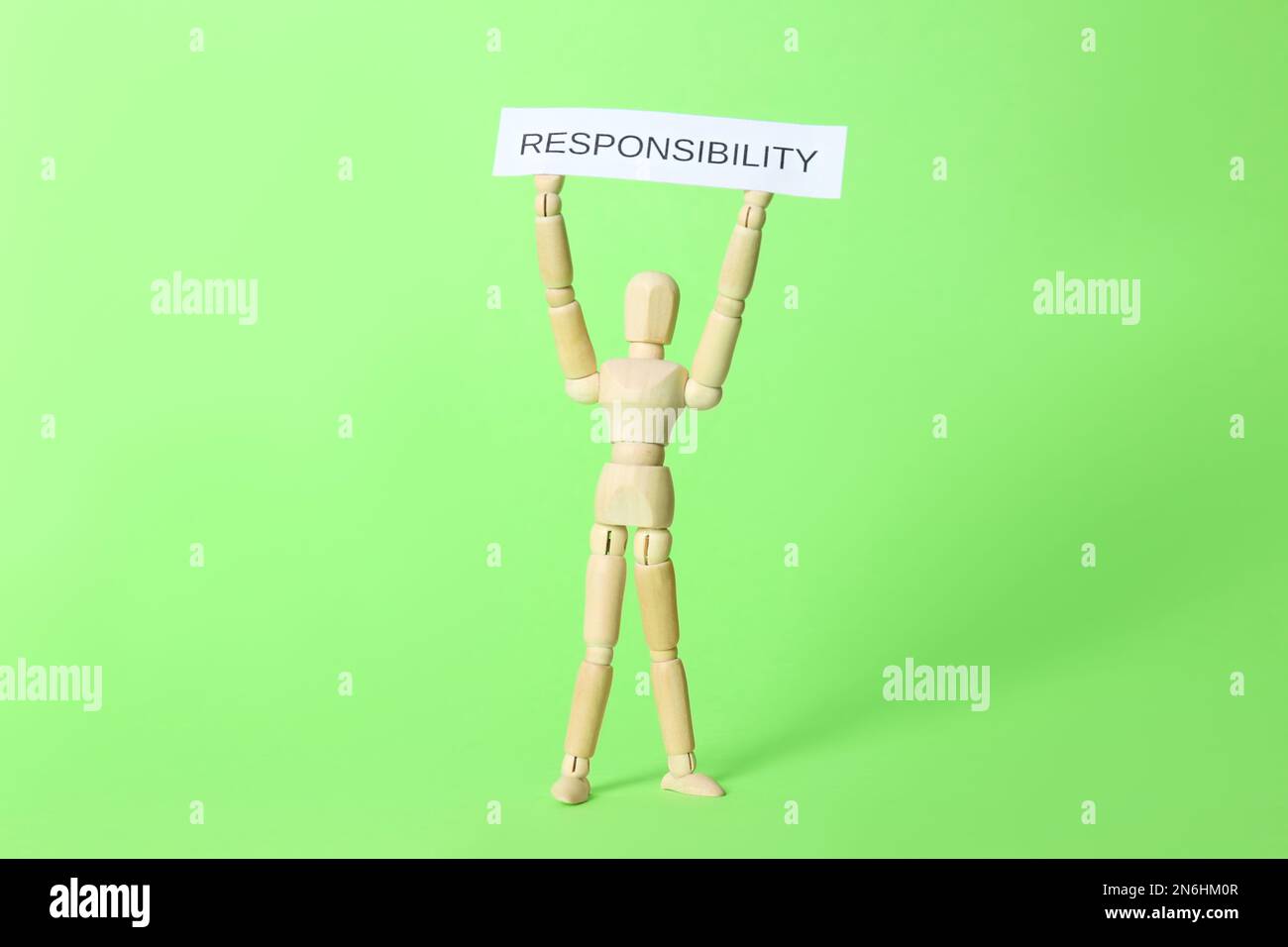 Wooden mannequin holding card with word Responsibility on light green ...