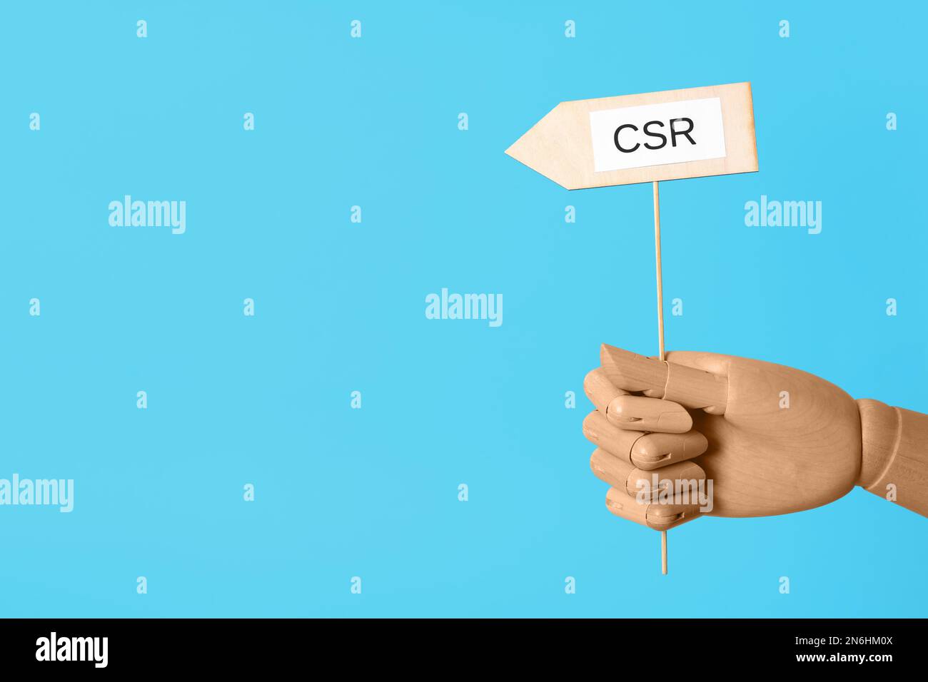 Wooden mannequin holding sign with abbreviation CSR on light blue ...