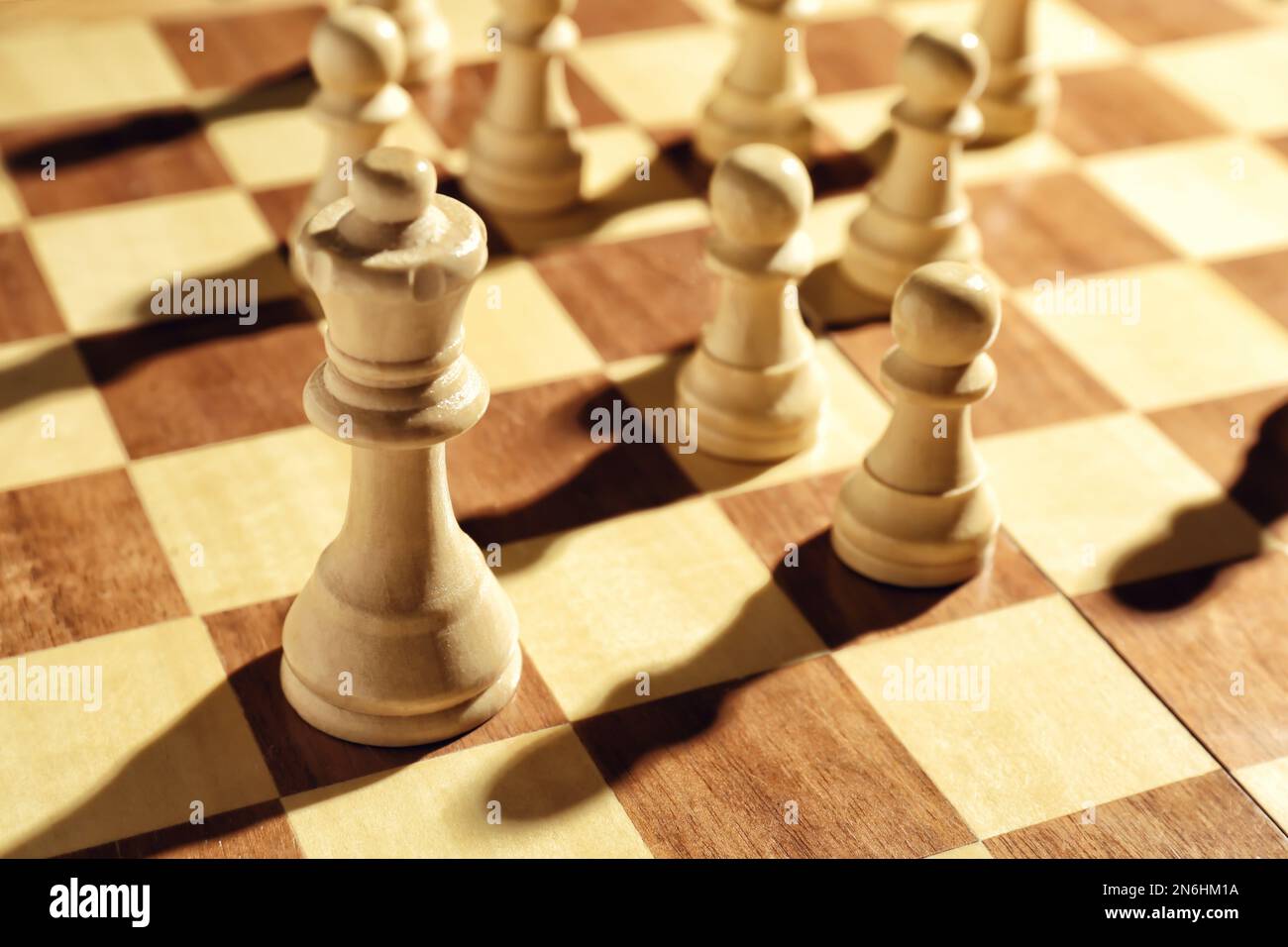 Queen and pawns on wooden chess board, closeup. Social roles concept ...