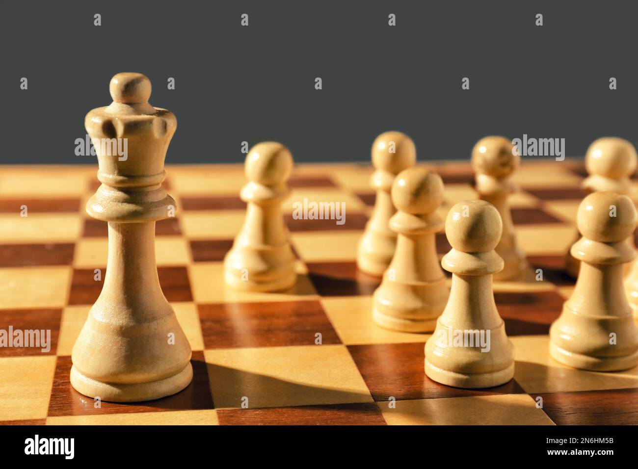 Queen and pawns on wooden chess board, closeup. Social roles concept ...