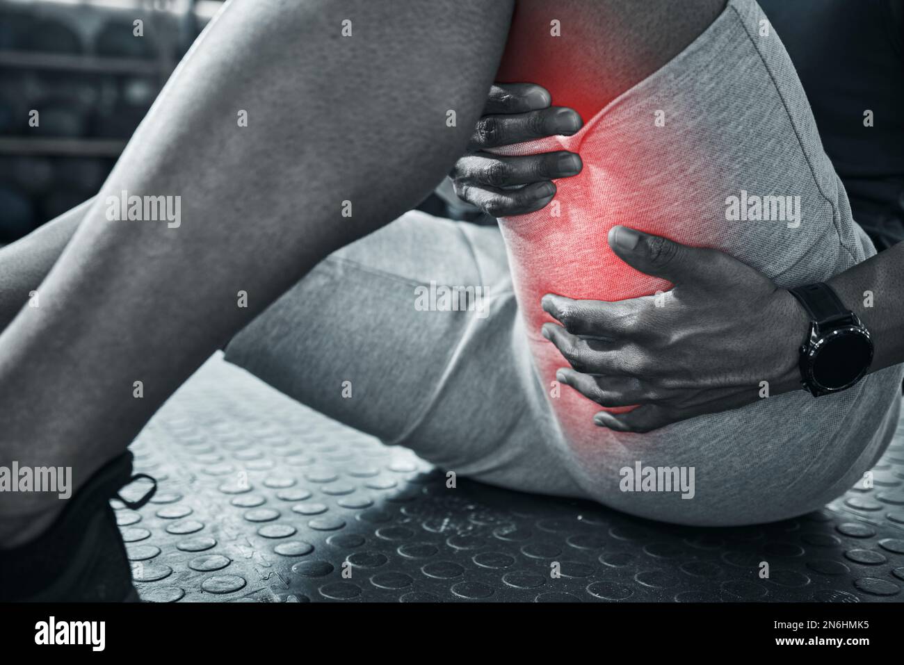 Hands of a trainer holding his thigh in pain. Red CGI used to find spots of muscular pain on the ...