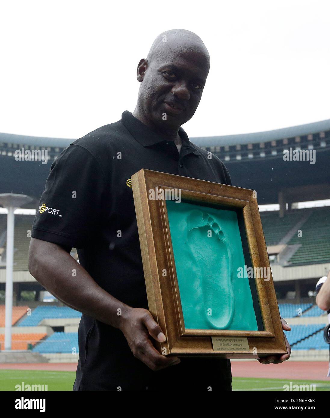 Canada's former sprinter Ben Johnson poses with his foot print in wet ...