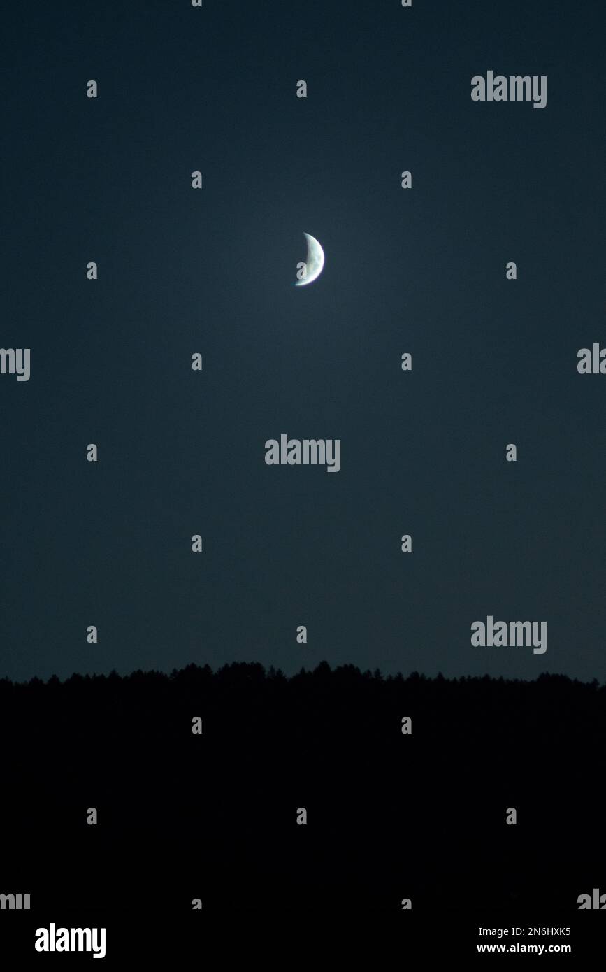 A vertical scenic shot of a crescent moon in the blue sky, backgrounds ...