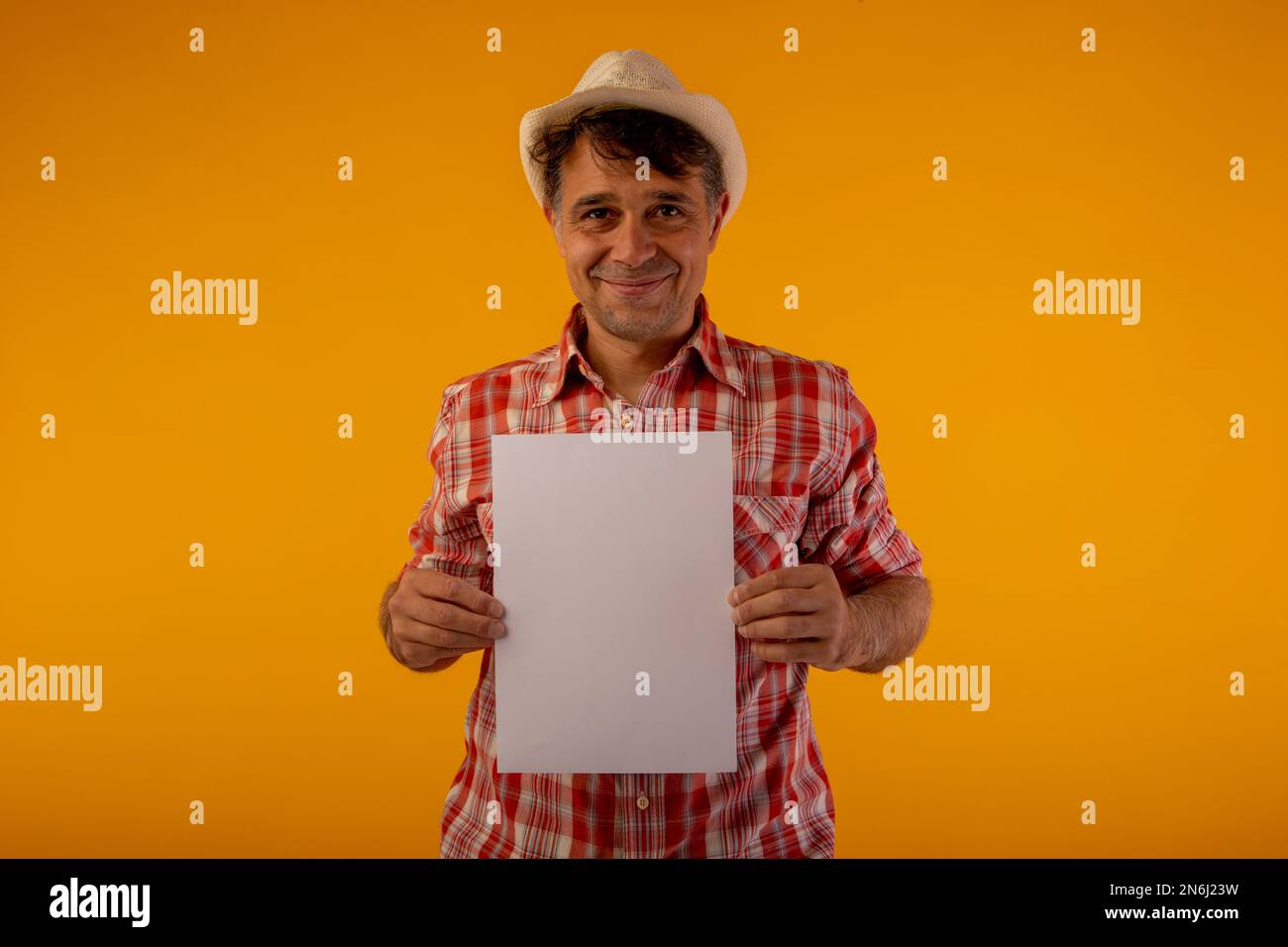 Adult man with hat and checkered shirt holding a blank cardboard on ...