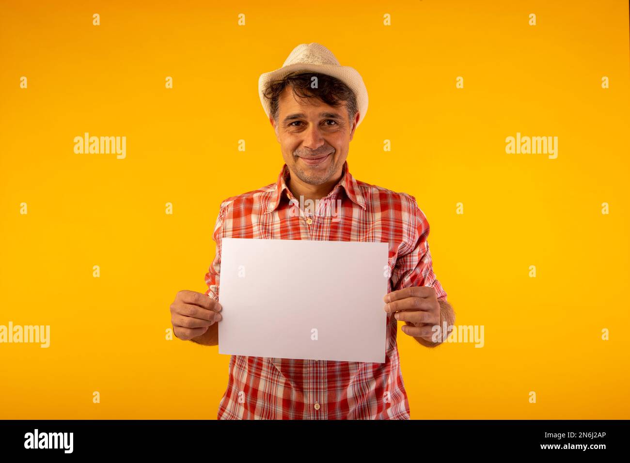 Adult man with hat and checkered shirt holding a blank cardboard on ...