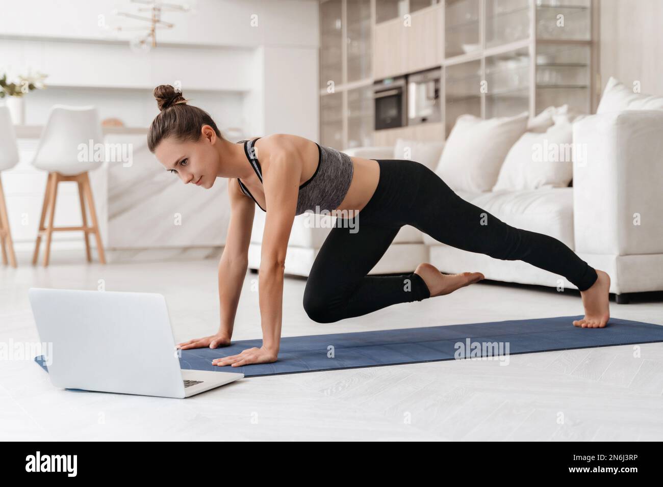 Young fit girl doing fitness exercise at home while watching online ...
