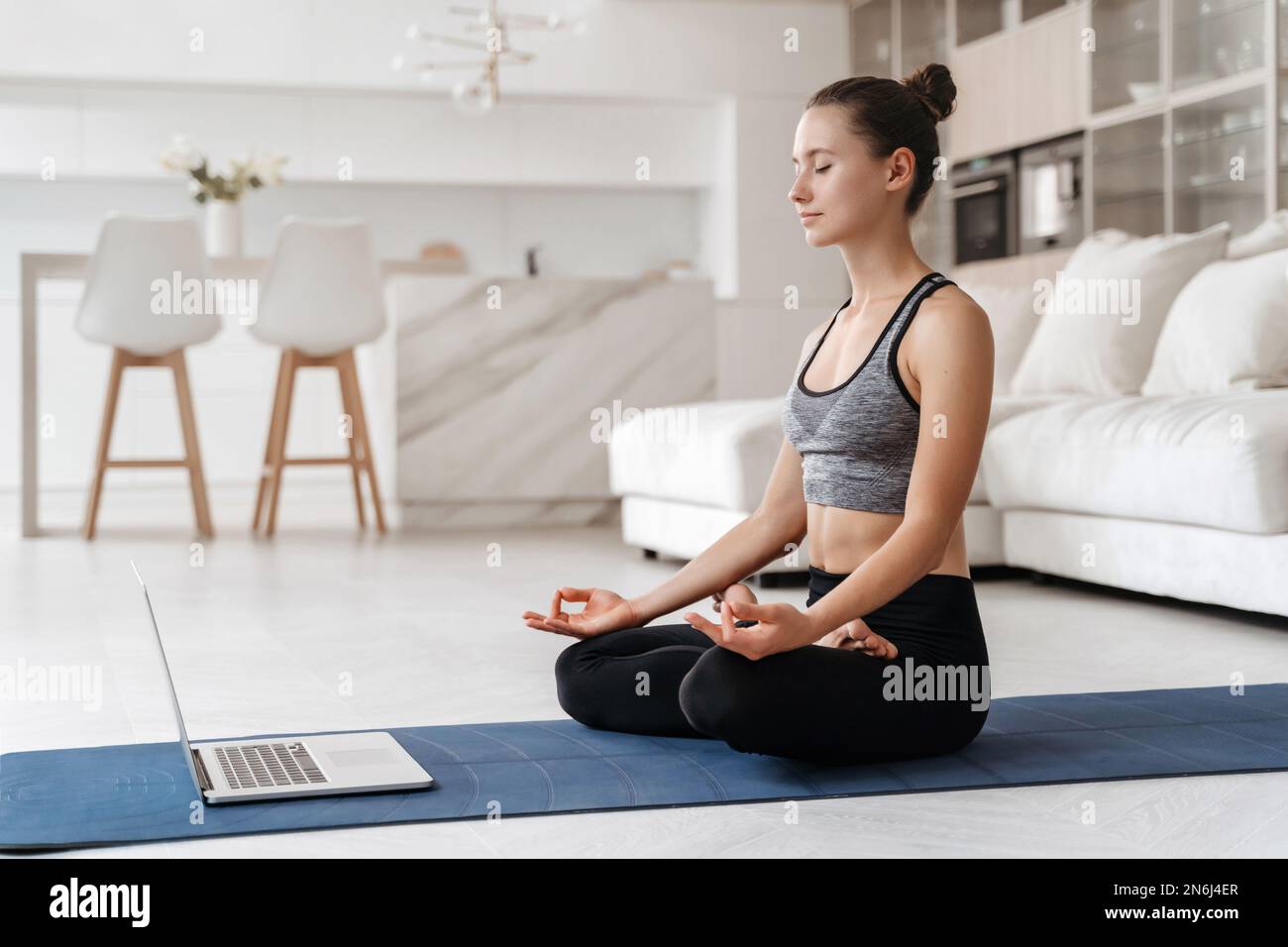 Fit young woman practicing meditation at home on exercise mat in her ...