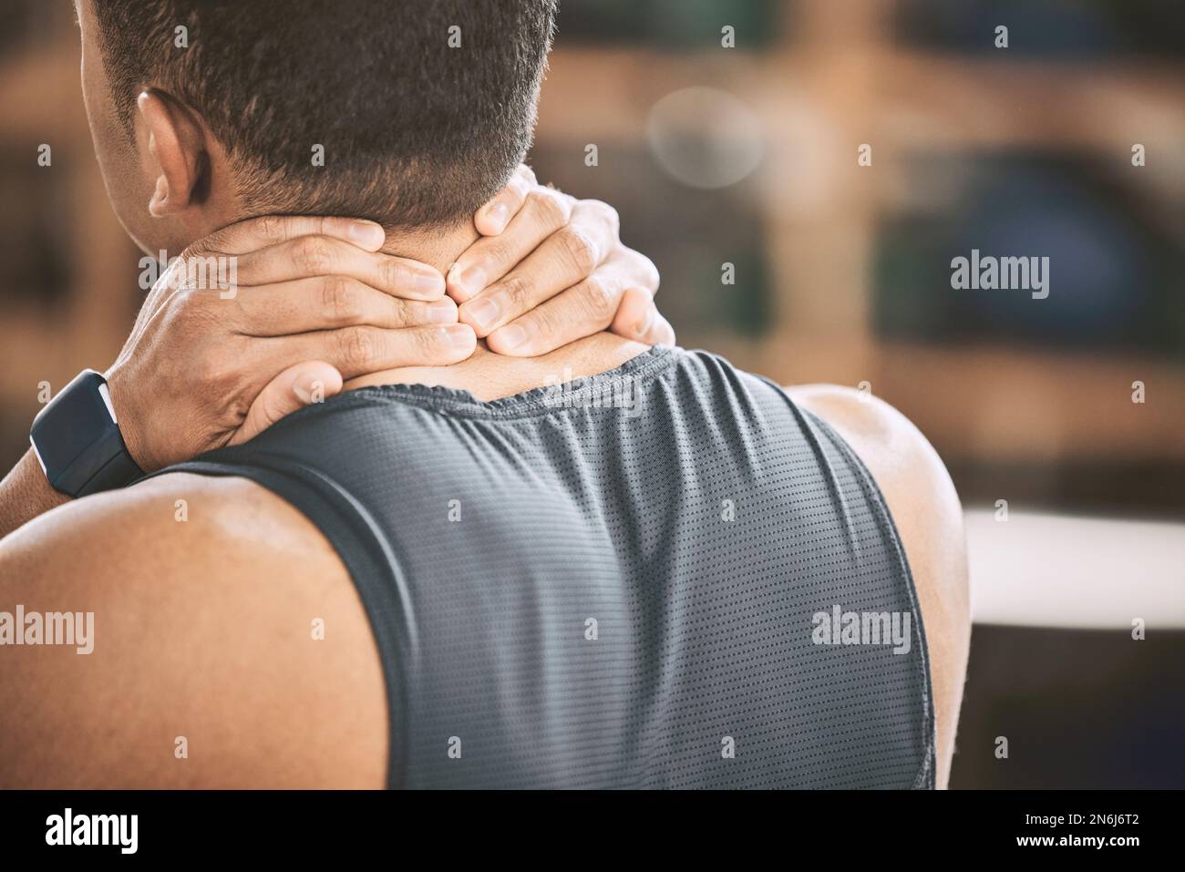 Back of a fit man experiencing pain. Athlete experiencing neck pain in ...