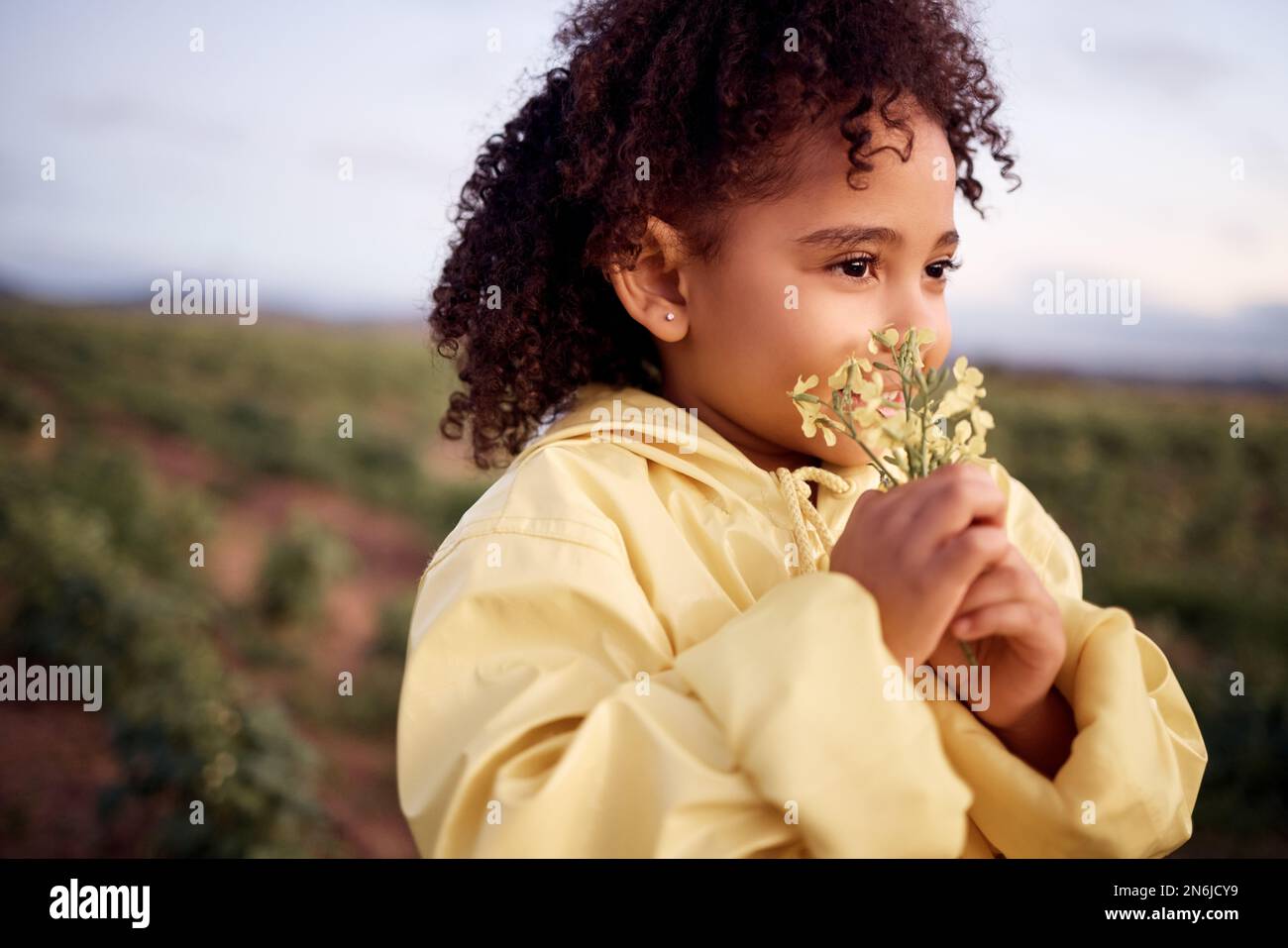 Children, farm and a girl smelling a flower outdoor in a field for ...