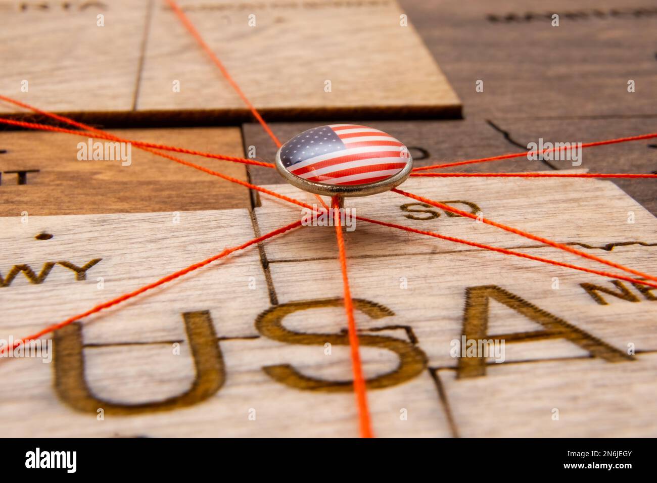 USA flag on the pushpin and red threads on the wooden map. Travel or ...