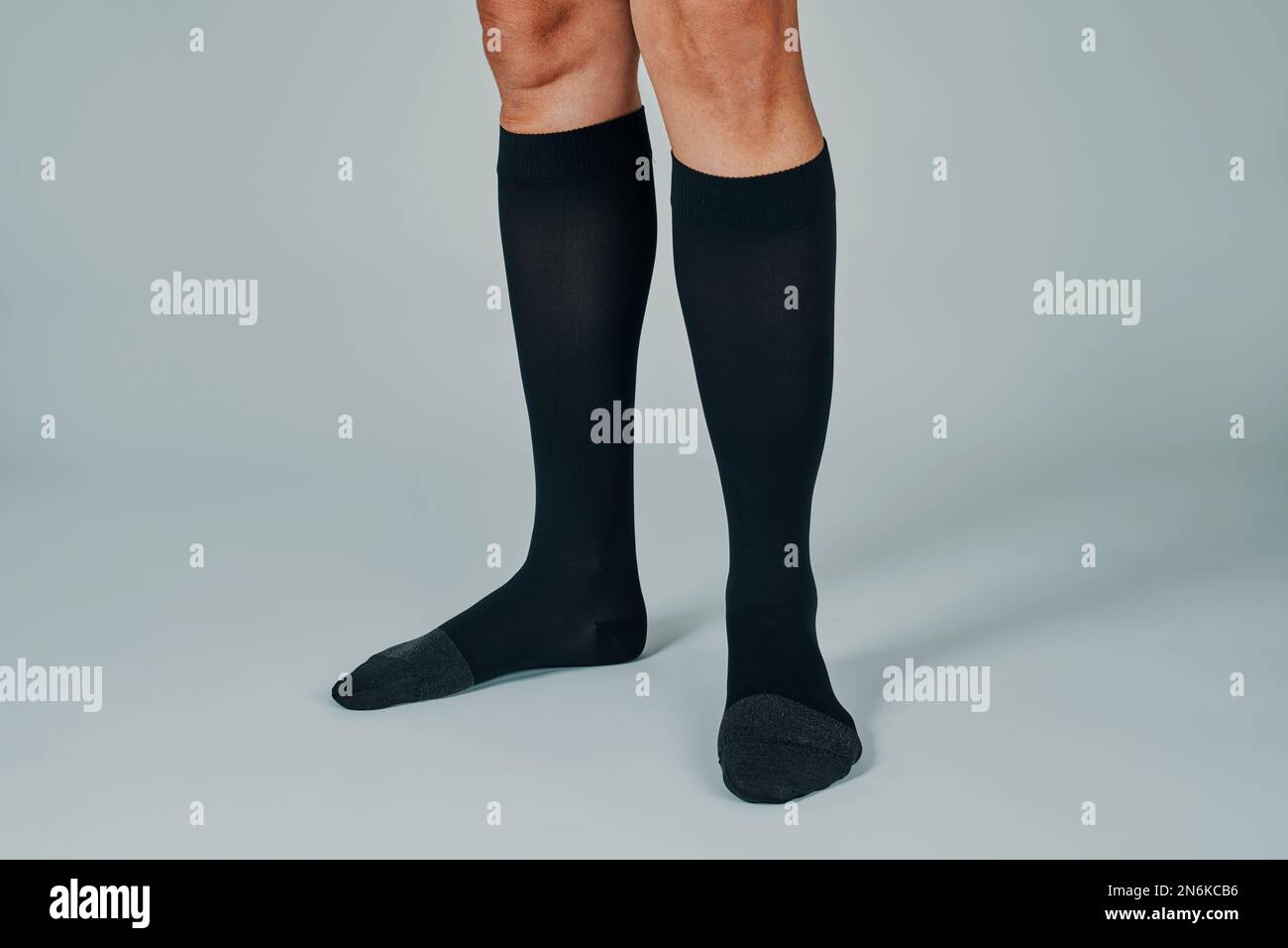 closeup of a man wearing a pair of black compression socks standing on ...
