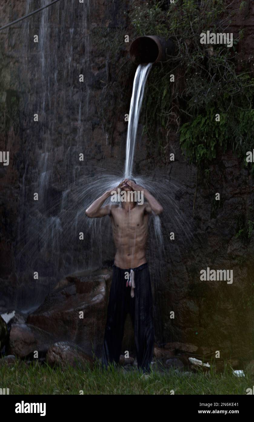 A Pakistani worker showers under a leaking water supply pipe, following ...