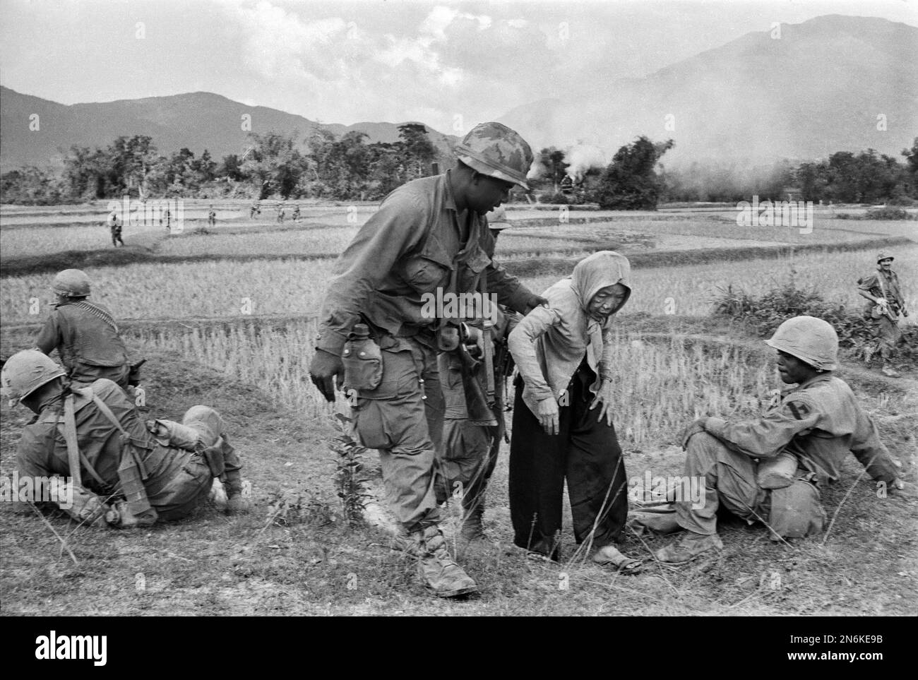 A U.S. air cavalryman lends a helping hand to an aged Vietnamese woman ...