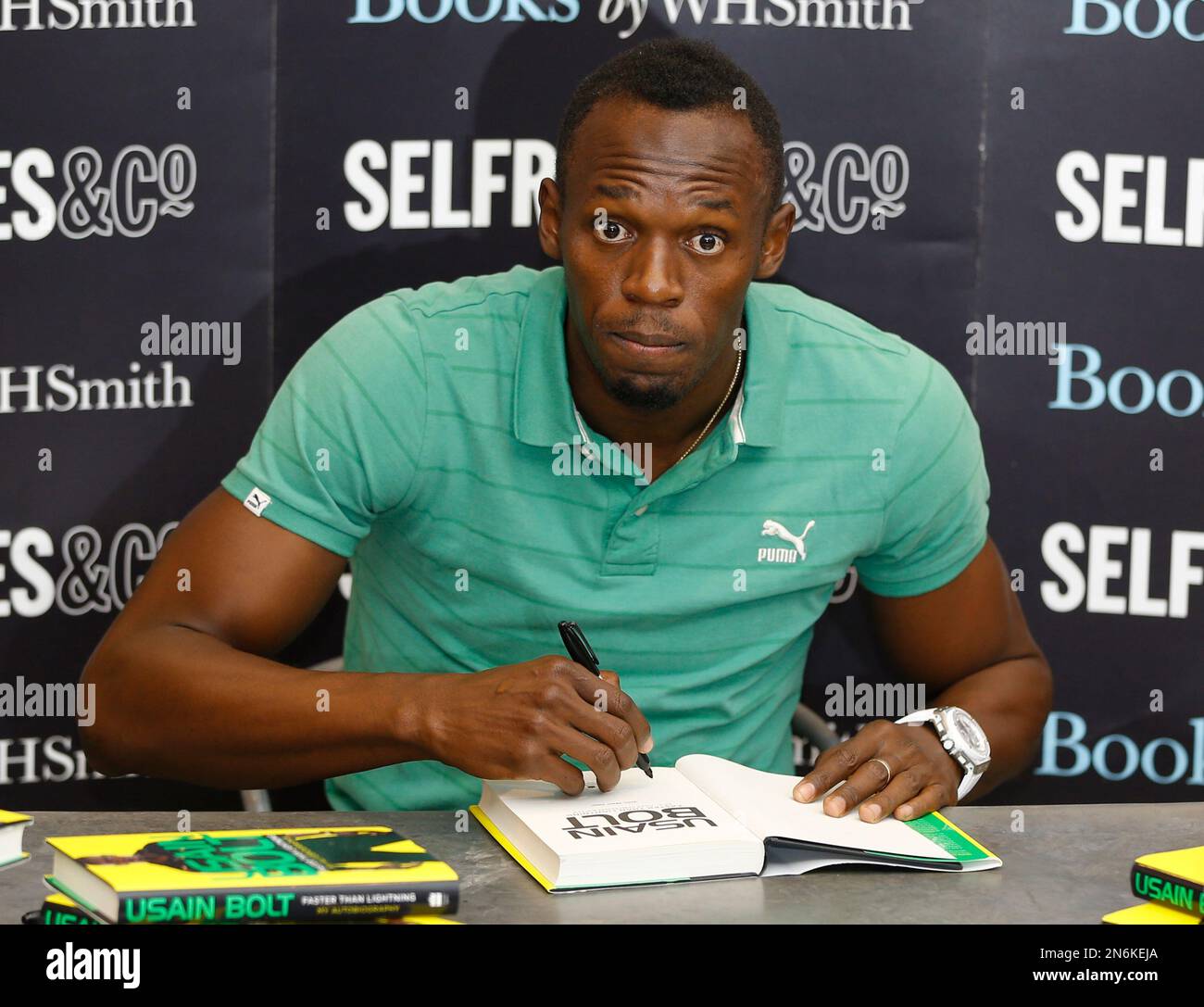 Jamaican athlete Usain Bolt, poses for the media as he signs a copy of ...