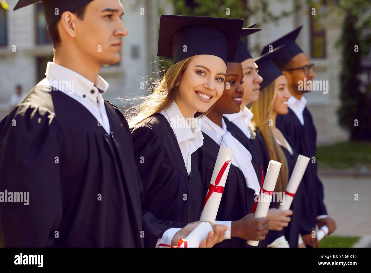 Group of multicultural people in graduation gowns and caps graduate ...