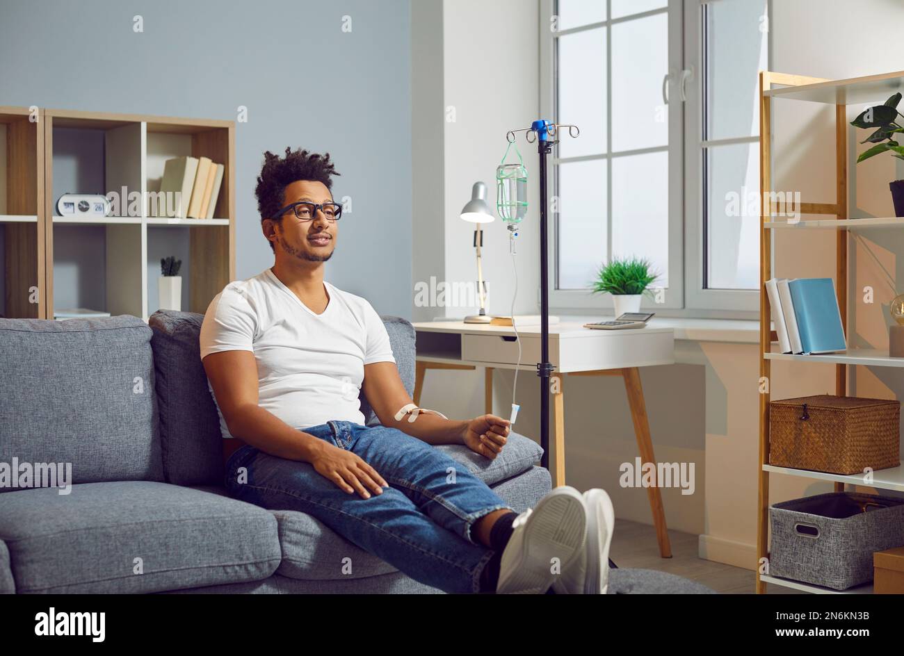 Young man receiving intravenous vitamin therapy through IV drip line ...