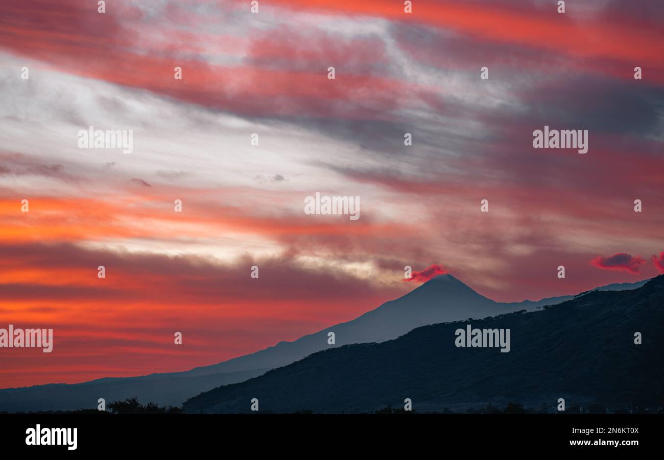 A silhouette view of Colima volcano under colorful dusk sky as seen ...