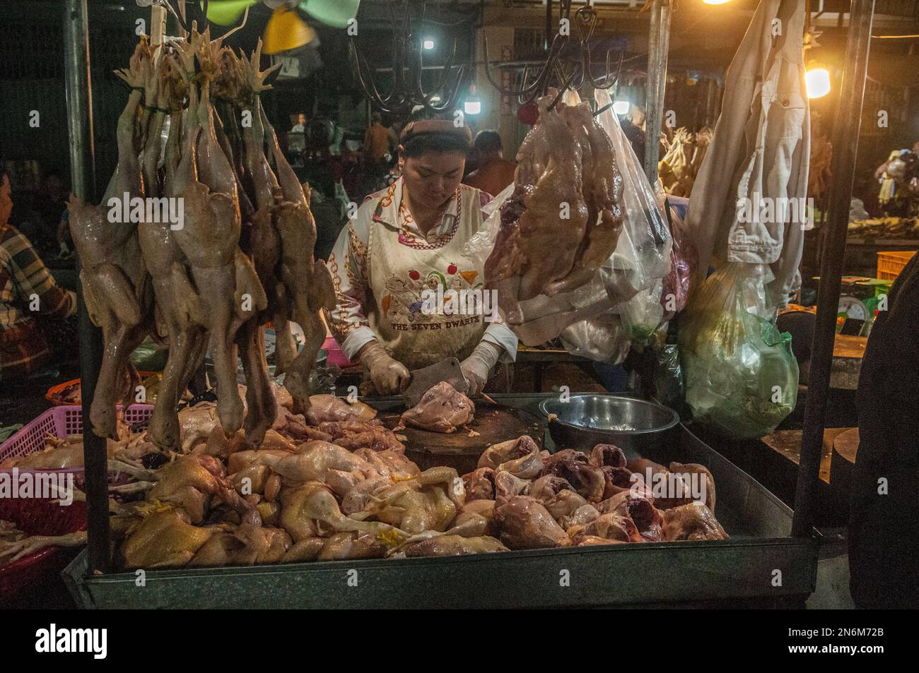 A Cambodian female butcher cuts raw chicken at the main wholesale ...