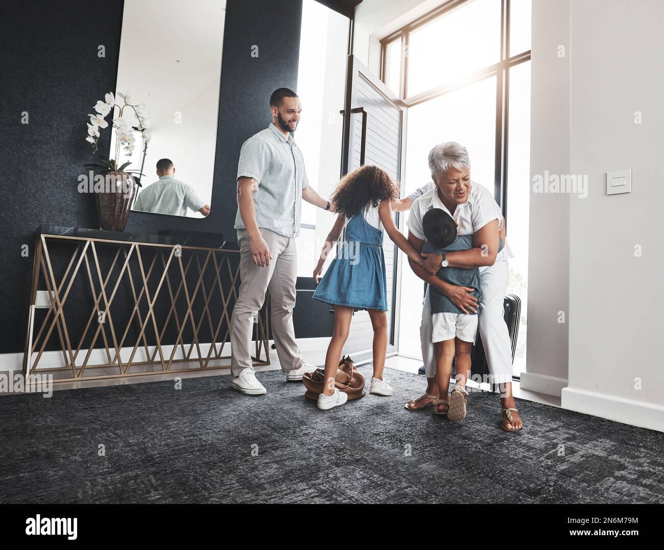 Family, grandmother and children hug as greeting in a home or house due ...