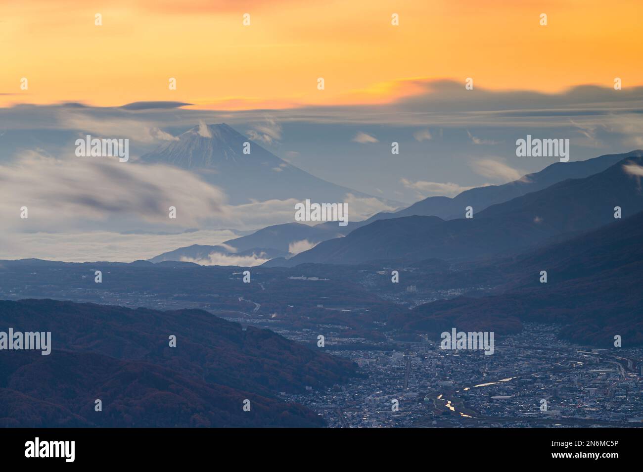 An aerial shot of a town and Mount Fuji in the distance around clouds ...