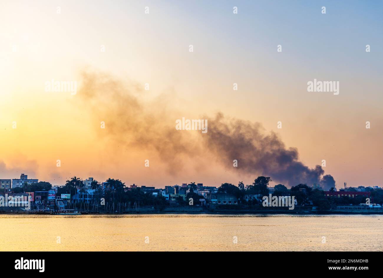 Thick polluting smoke rises at dusk from the banks of the Hooghly River ...