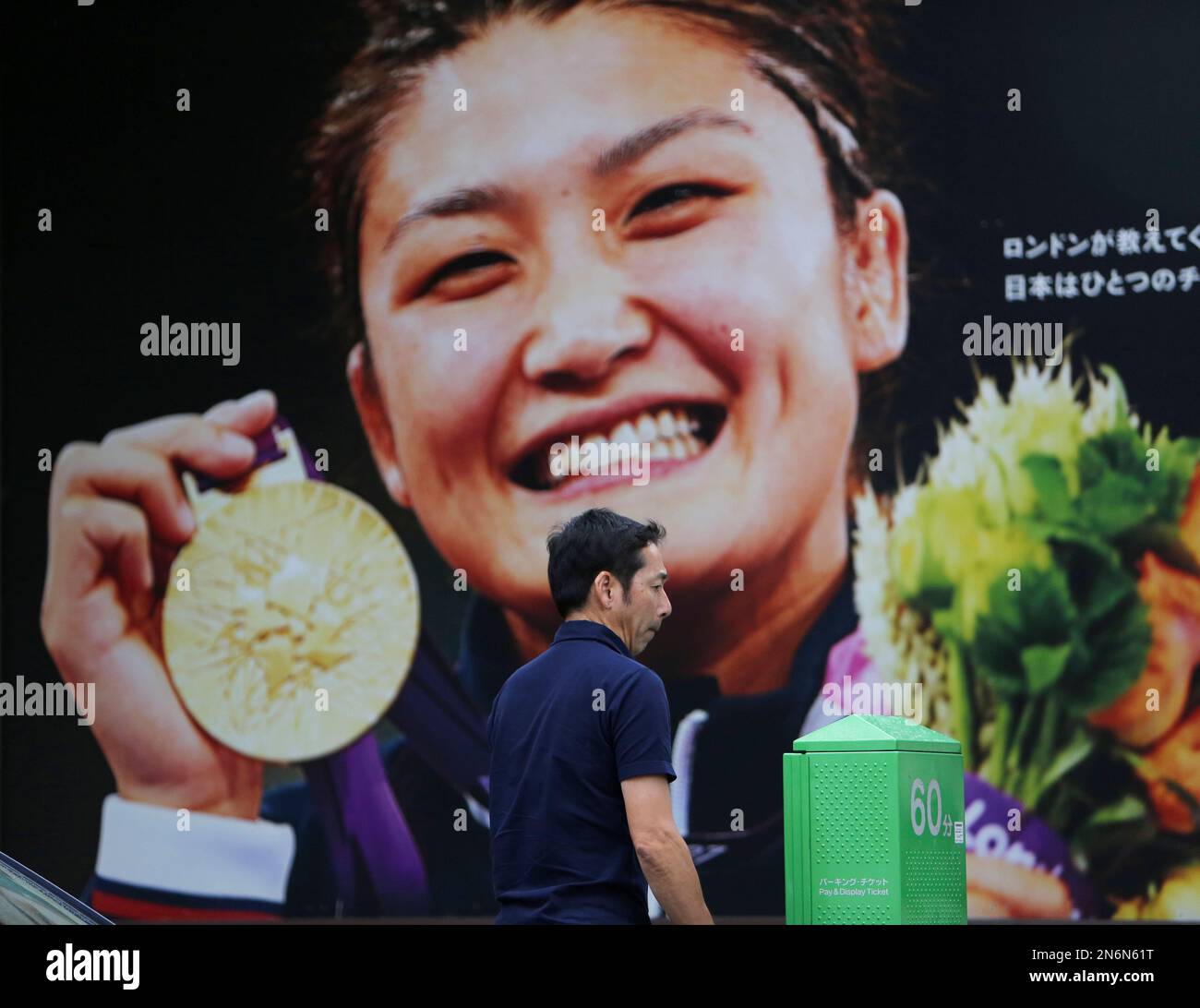 A man walks past a billboard featuring Japanese Olympic wrestling gold ...