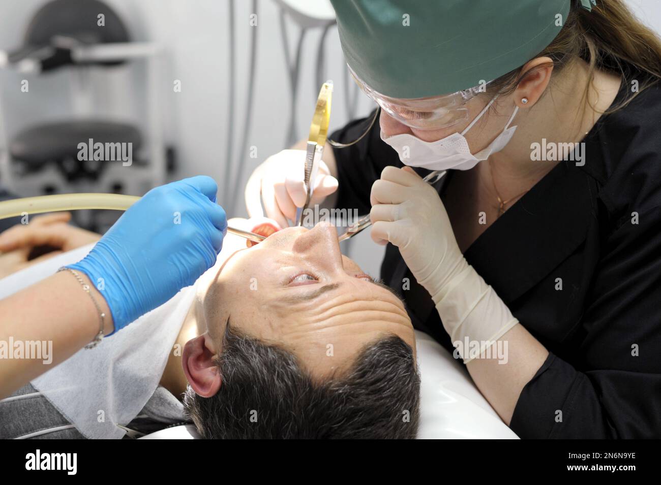 adult man praying with his eyes looks at the doctor who tears his tooth ...
