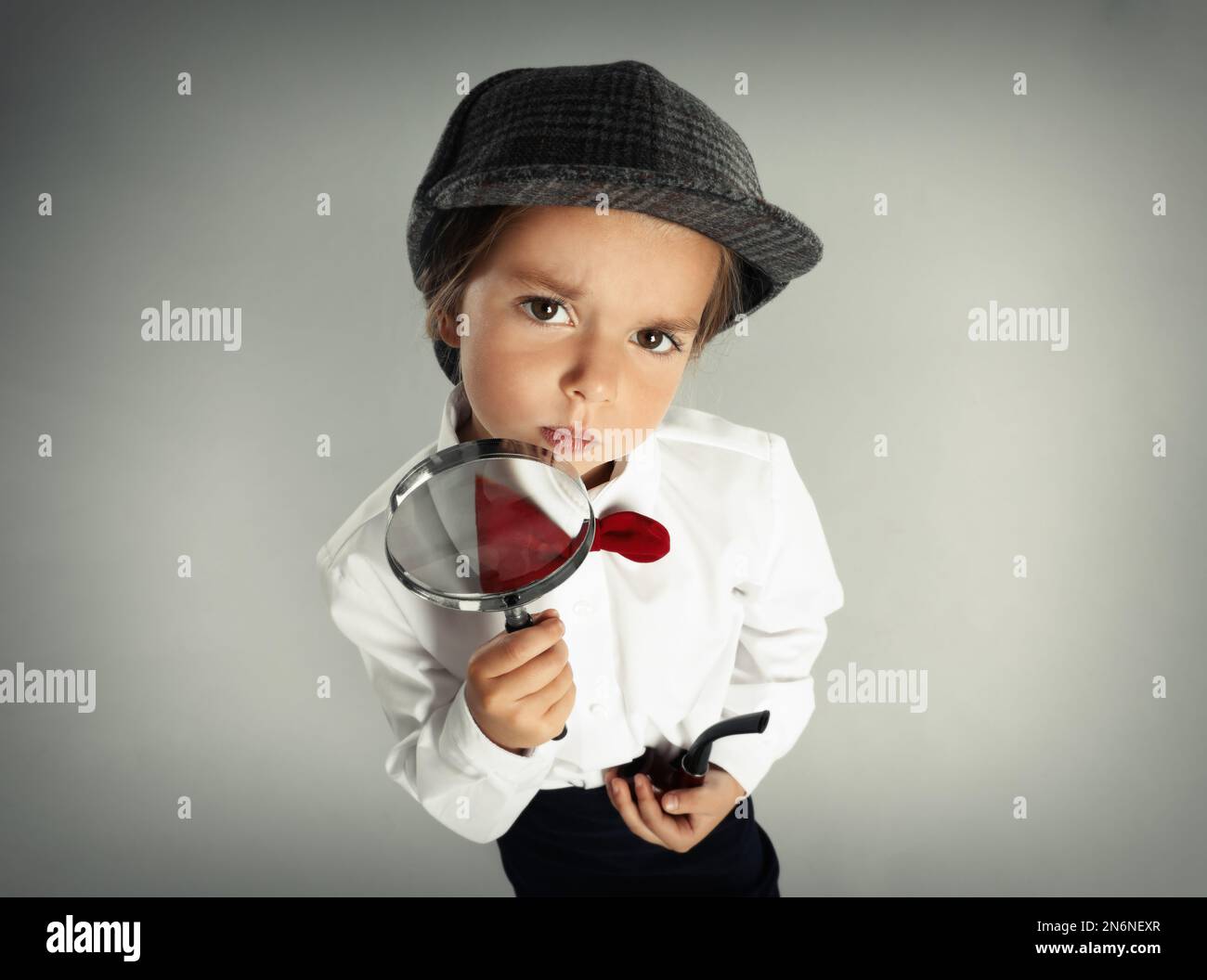Cute little child in hat with smoking pipe and magnifying glass playing ...