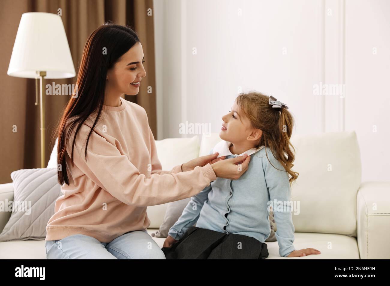 Young mother helping her little child get ready for school at home ...