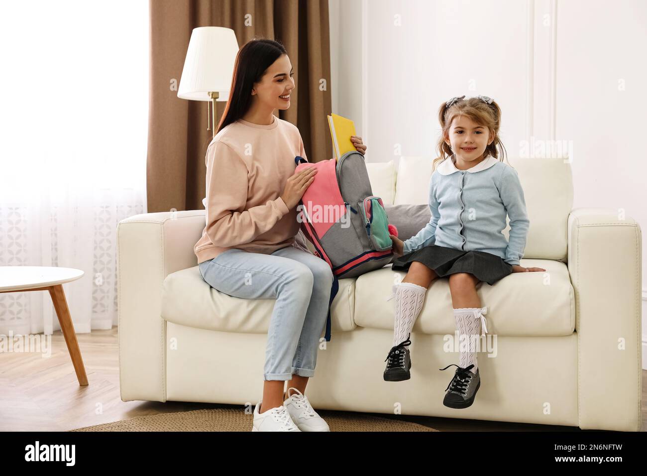 Young mother helping her little child get ready for school at home ...